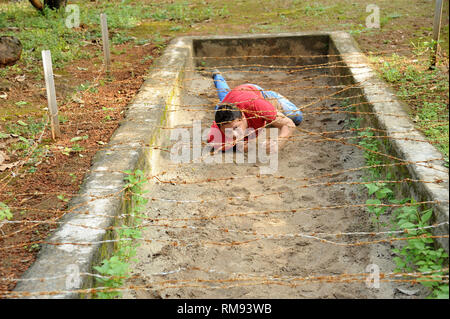 A man crawling under barbed wire during strength race Legion Run held ...