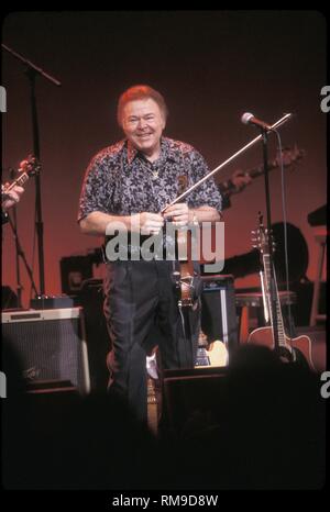 Musician Roy Clark is shown performing on stage during a "live" concert ...