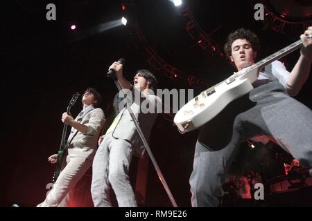 The Jonas Brothers are shown performing on stage during a "live ...