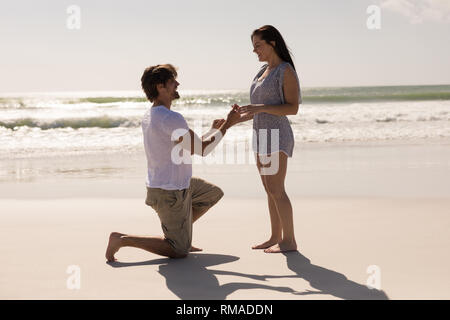 Calm man standing on his knee and asking his girlfriend to marry him ...