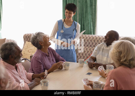 Female doctor interacting with senior people in living room Stock Photo ...