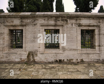 Detail of a stone wall with open lattice windows in front of a cemetery ...