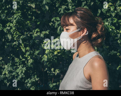Beautiful asian woman wearing white protective N95 dust mask on green ...