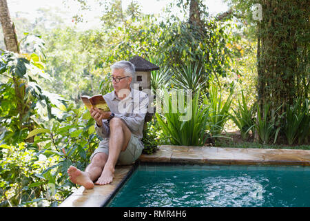 Man reading book at swimming pool Stock Photo - Alamy