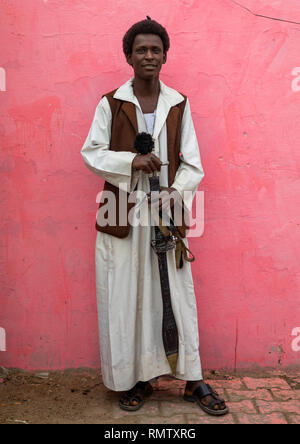 Beja tribe warrior with his sword in front of a pink wall, Red Sea ...