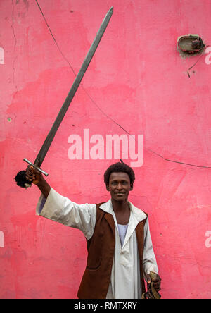 Beja tribe warrior with his sword in front of a pink wall, Red Sea ...
