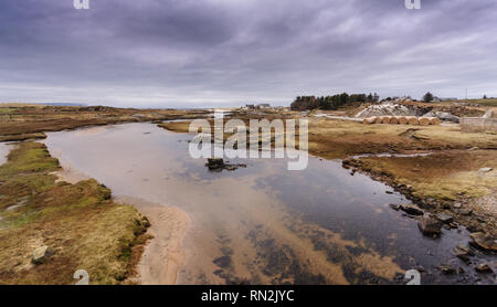 A small river forms an estuary across coastal salt marsh at Arisaig in ...
