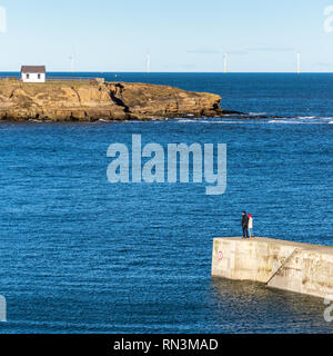 Tynemouth, England, UK - February 4, 2019: People walk dogs while waves ...