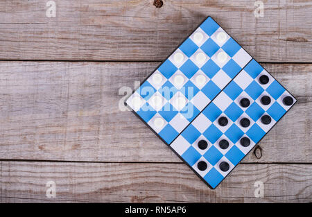 A blue and white checkers board with black and red game pieces, set up ...