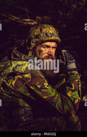 Young soldier with sad bearded face in military helmet and camouflage ...