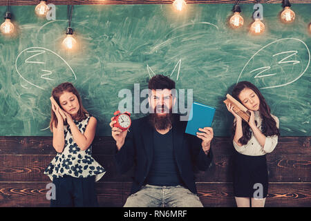 Angry Bearded teacher in classroom sits at desk. Back to school ...
