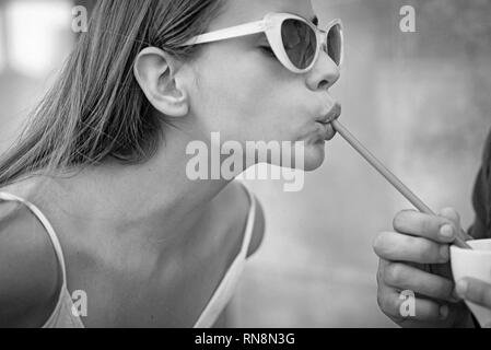 Beautiful woman sipping through a straw outdoors while sitting at a ...