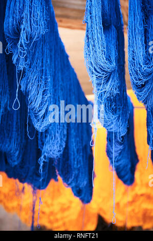 Bundles of wool string hang from bamboo poles overhead to dry in the ...