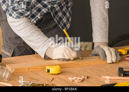 Carpenter marking pine wood plank for cutting in woodwork workshop ...