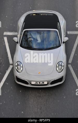A silver Porsche 911 convertible photographed from above as it drives ...