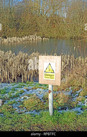Temporary Danger Deep Water sign beside a frozen pond in winter Stock ...