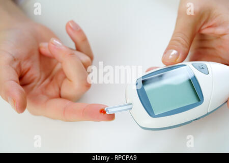 Woman hands poking finger to check glucose or blood sugar level with ...
