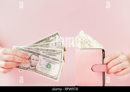 Dollars and pink wallet with credit card in woman's hands on pink ...