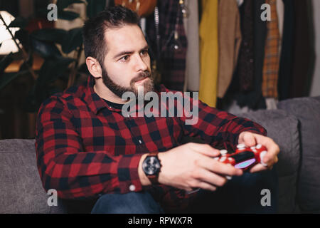 Portrait of nervous gamer guy playing video games on computer wearing ...