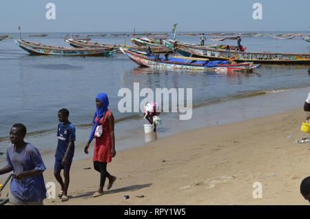 A crowded beach in Mbour, Senegal, with fishers landing their catch and ...