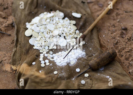 Bushmen woman of the San people making jewelry of ostrich egg shell ...