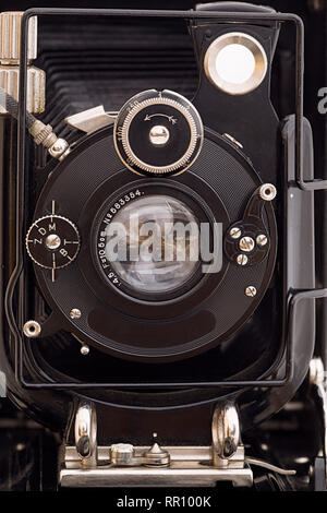 A close-up of an old film camera, vertical shot with a black background ...
