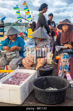 Female fishmongers wearing conical hats selling fresh fish at ...