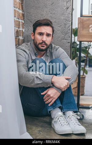 depressed man sitting in a corner of a room Stock Photo - Alamy