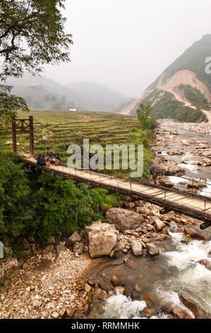 group of people sitting at wooden bridge over the river with a focus on ...