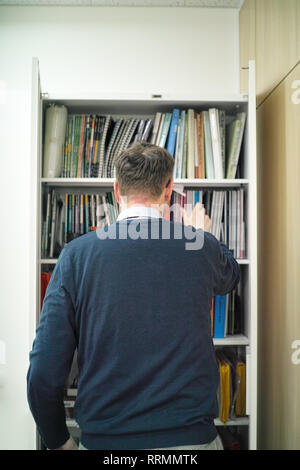 A man reaching for a folder in a big filing cabinet at work Stock Photo ...