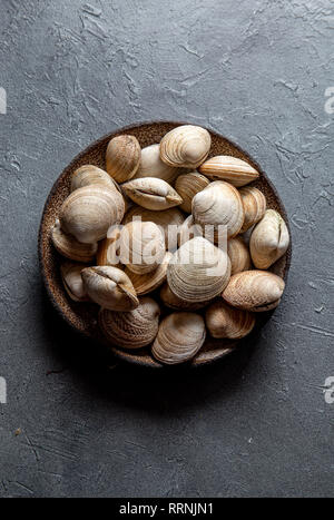 Fresh clams in textured white bowl on marble surface. Seashells, red ...