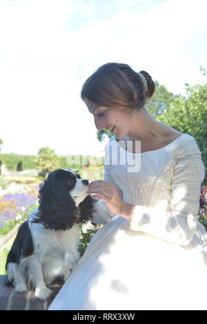 A young Queen Victoria and her dog Dash sit on a wall in the garden at ...