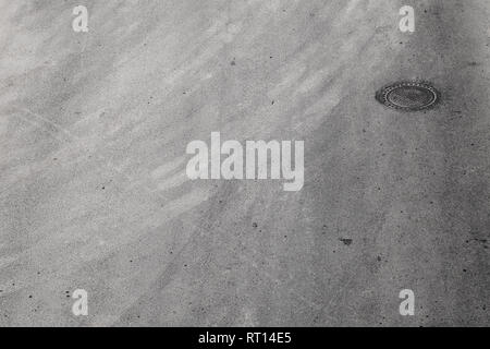 Round hatch in urban asphalt road pavement. Russian relief text on the ...