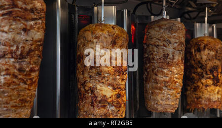 Greek Gyros spit on a grill. A man cutting meat off Stock Photo ...