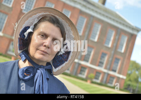 An old stern looking Victorian woman in a bonnet stands in front of ...