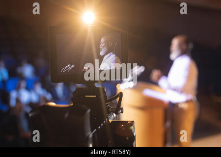 Camera recording businessman giving speech in auditorium Stock Photo ...