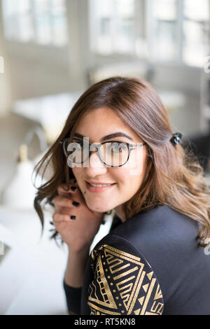 Portrait of smiling female interior designer sitting at office desk ...