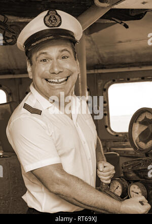 A laughing sailor officer in the uniform is steering the ship with a ...