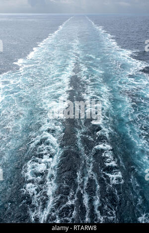 The wake in the ocean water behind a ship shows the turbulent effect of ...
