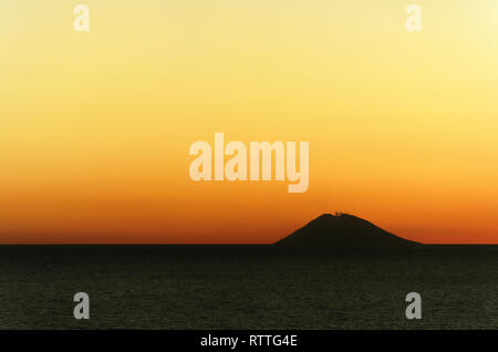 Distant Stromboli volcano with blue sea and sky on a hazy sunny day ...