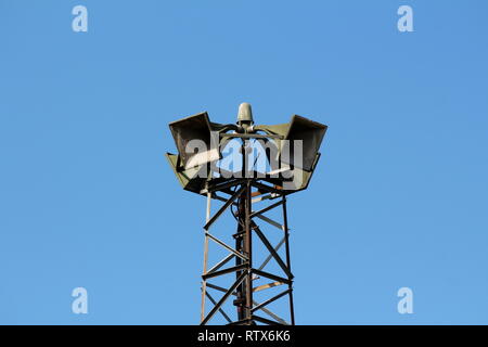 Tall metal structure holding four large public civil defence warning ...