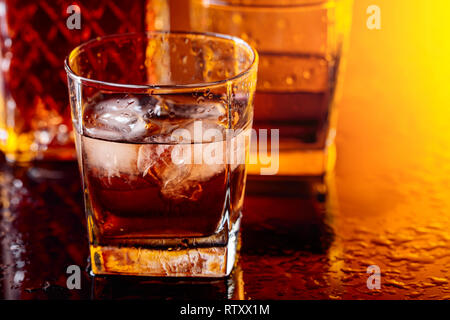 Glass of whiskey with natural ice. Color light Stock Photo - Alamy