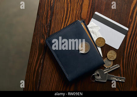 leather wallet, keys, cheque, coins and credit cards on wooden table ...