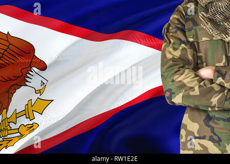 Crossed arms Samoan soldier with national waving flag on background ...
