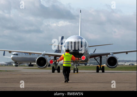 A airside operations member of staff guides in planes at Heathrow ...