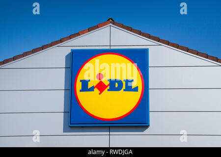 The Lidl sign and logo against a bright blue sky on the front of the ...