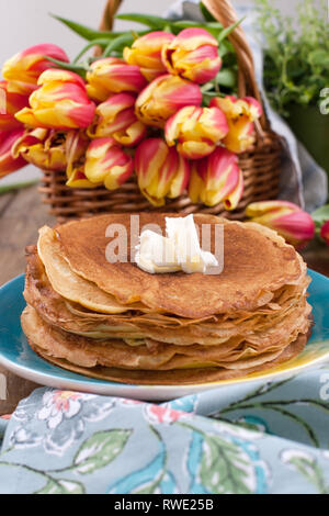 Lots of thin pancakes on a wooden background or table, and a basket ...