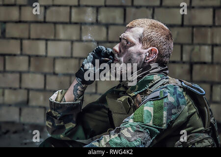 Special forces soldier smoking a cigarette while sitting in a ruined ...