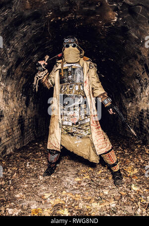Post apocalyptic survivor holding a pistol and machete in an abandoned ...