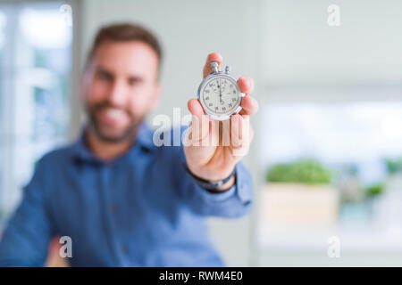 Hispanic man with beard holding stopwatch looking positive and happy ...
